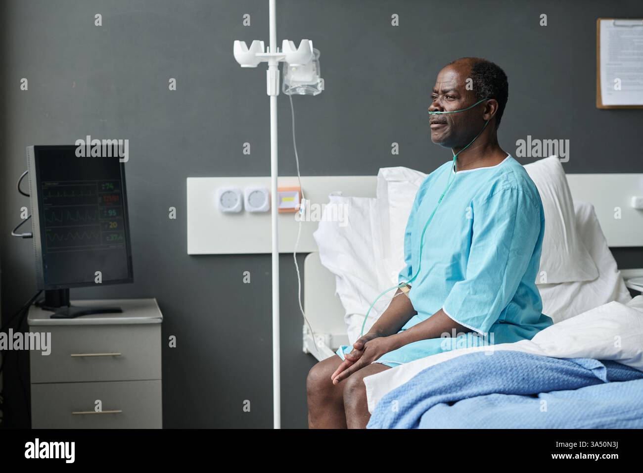African American elderly man with dropper sitting on bed in hospital ...