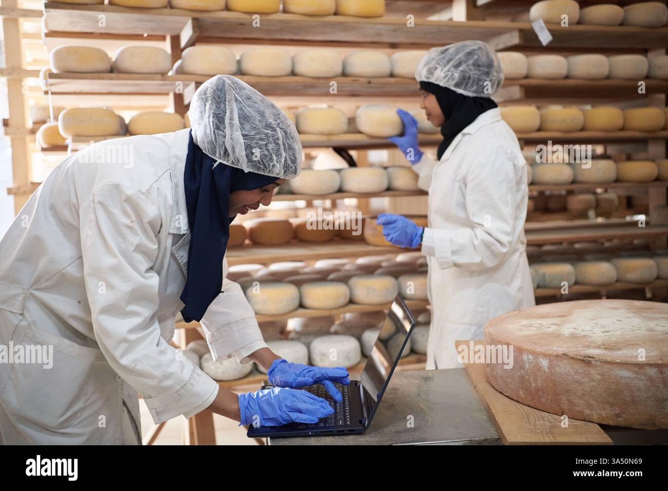 Middle Eastern female workers in hijab and white uniforms controlling ...