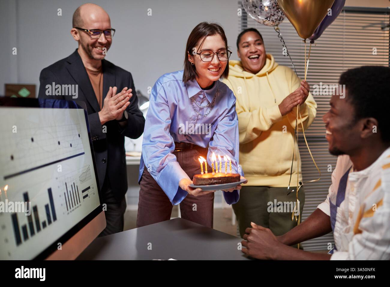 Diverse group of colleagues applauding while bringing surprise Birthday ...
