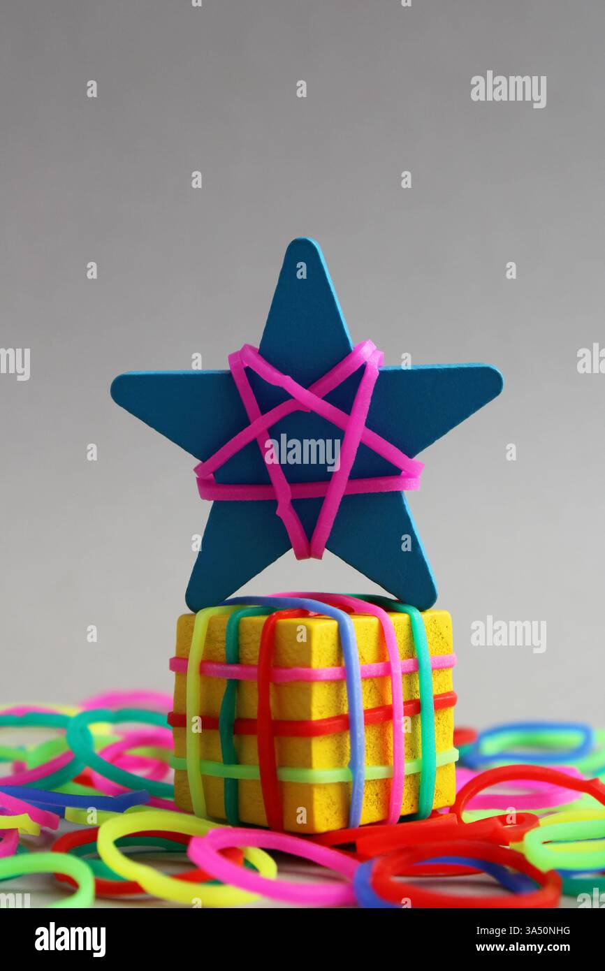 Colorful rubber bands tied to a cube and a wooden star - vertical ...