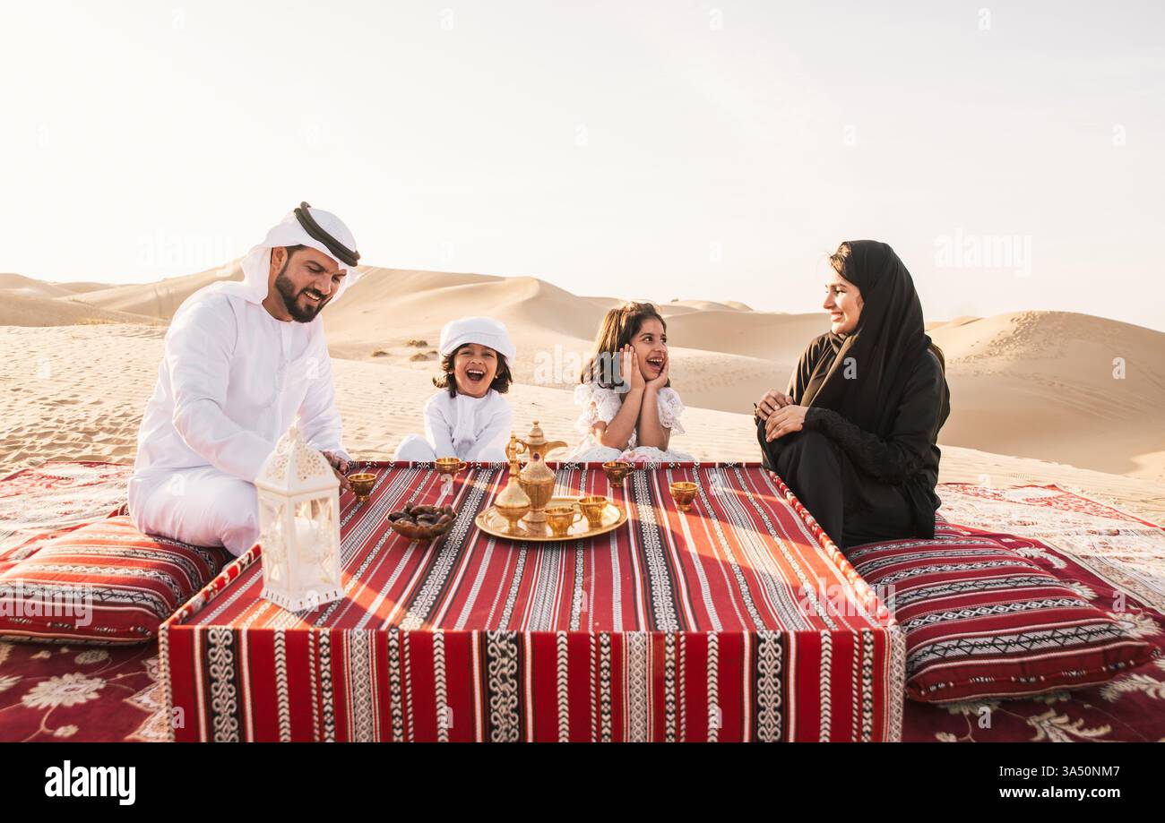 Arab family sitting at table having picnic in desert at sunset Stock ...