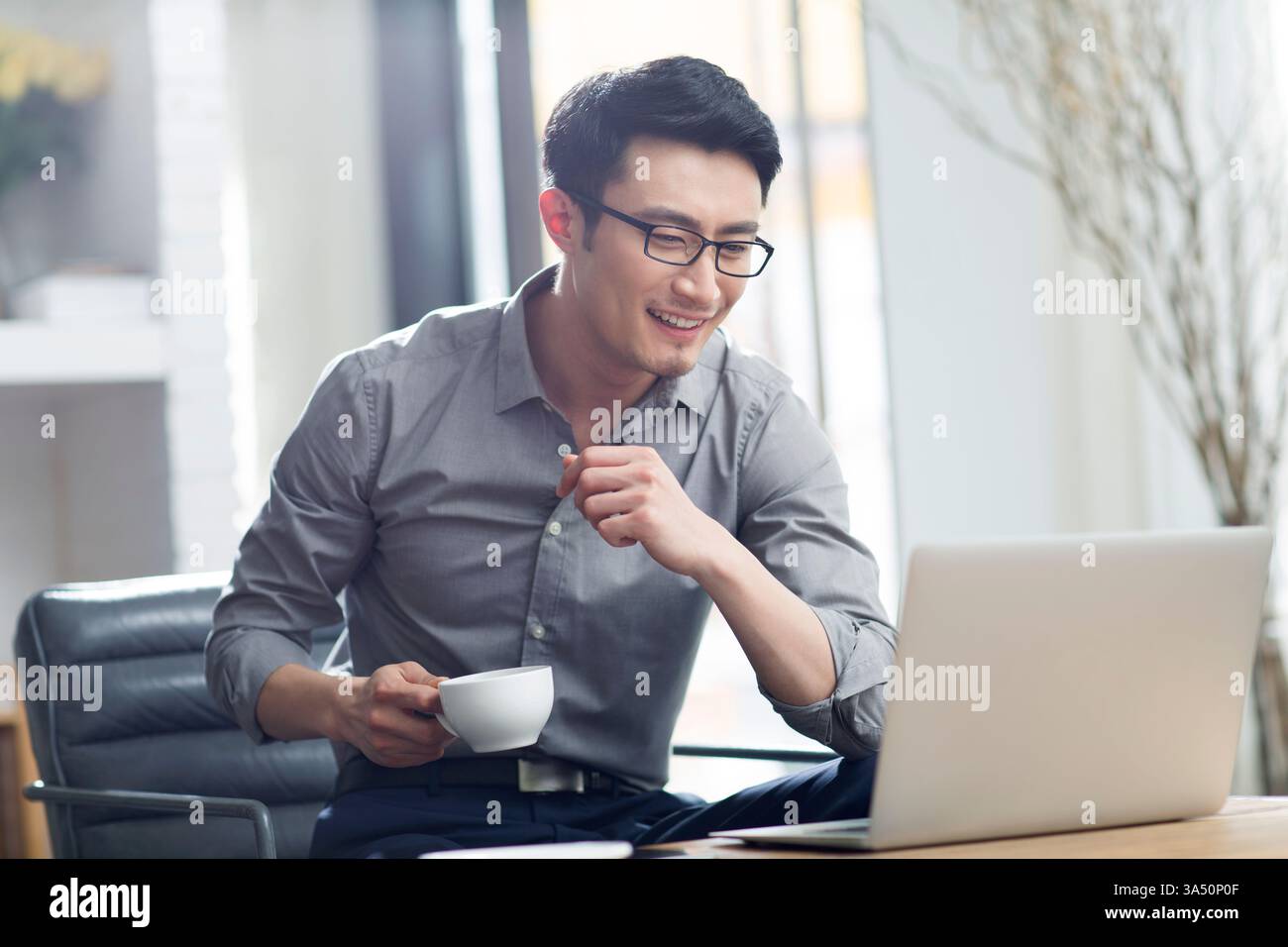 Young Chinese man working with laptop in office Stock Photo - Alamy