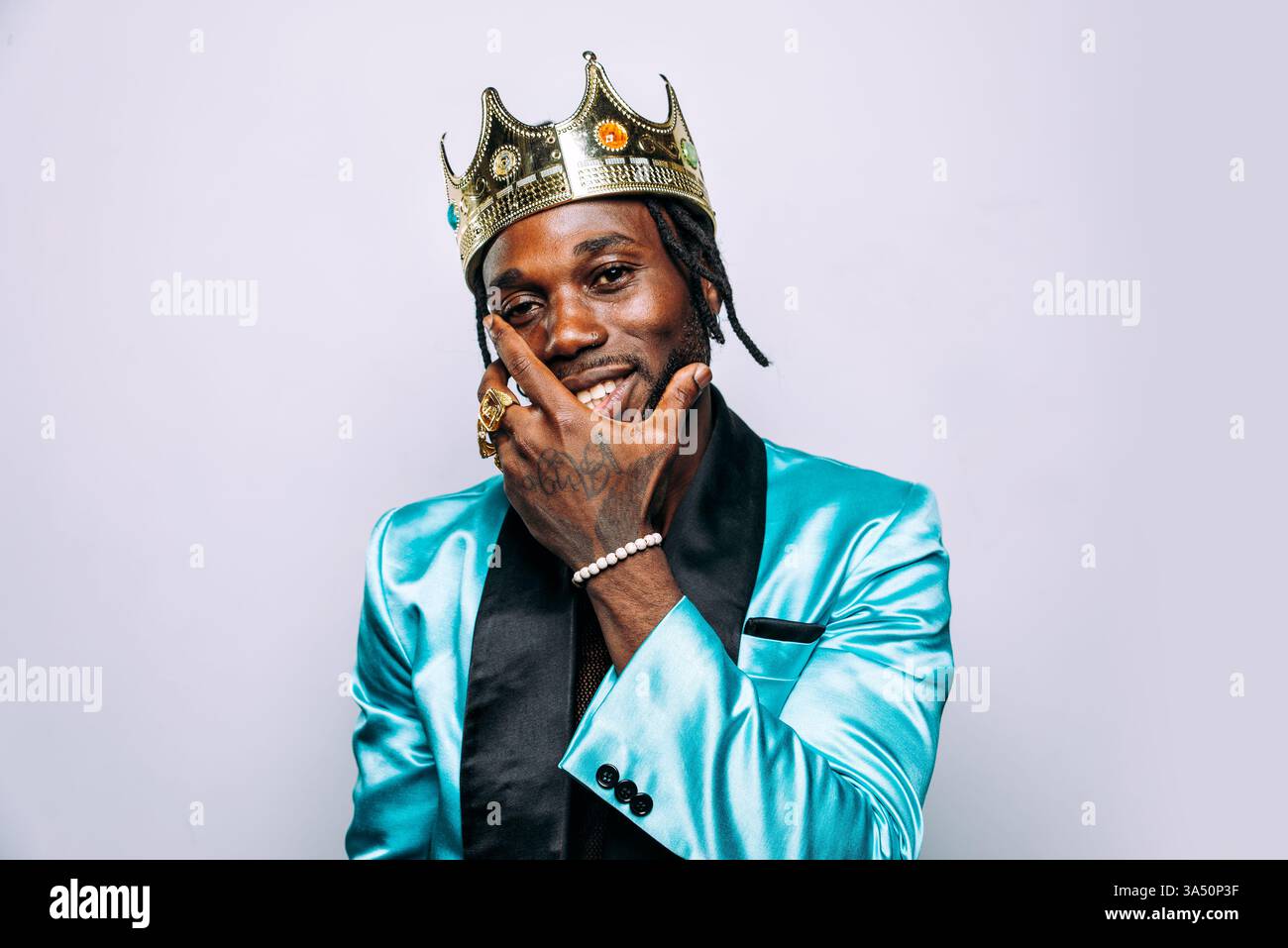 Smiling African American male wearing crown and jewels with hand on ...