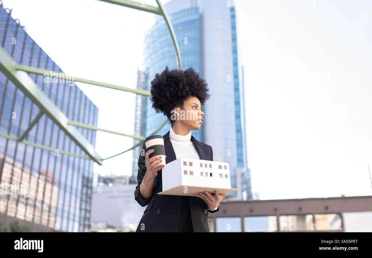 Low angle of cheerful African American female architect standing with ...