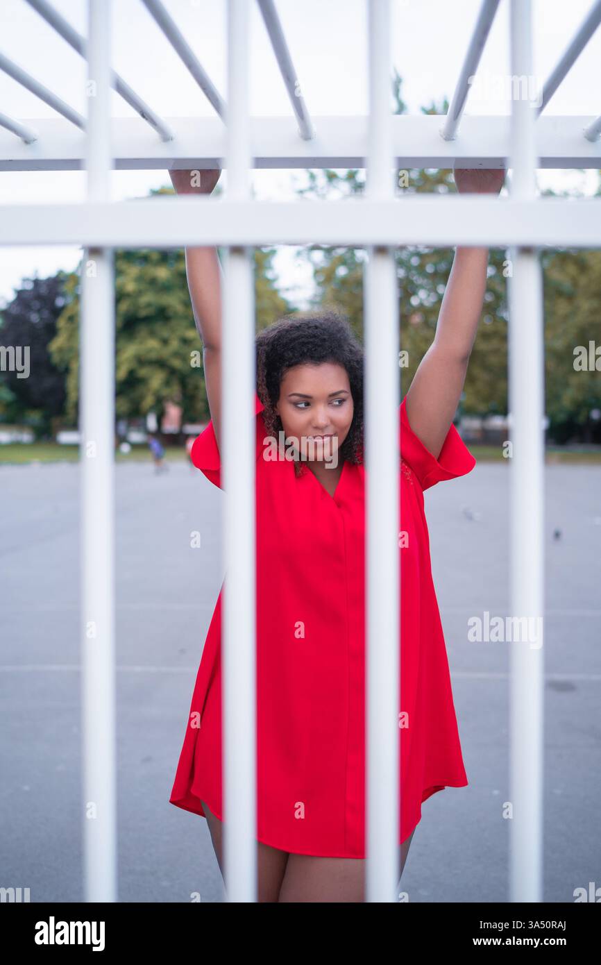Black woman with curly hair looking away raising arms standing behind ...