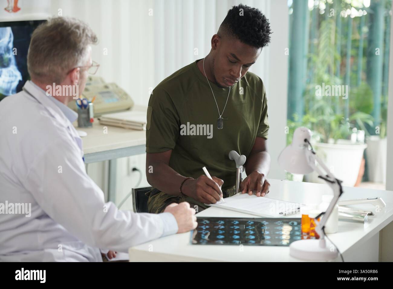 Black military man signing documents in medical office Stock Photo - Alamy