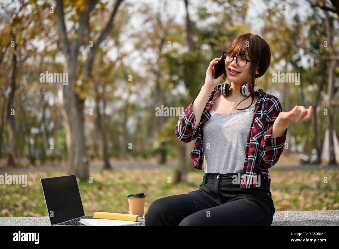 Smiling Asian female college student wearing eyeglasses and headphones ...