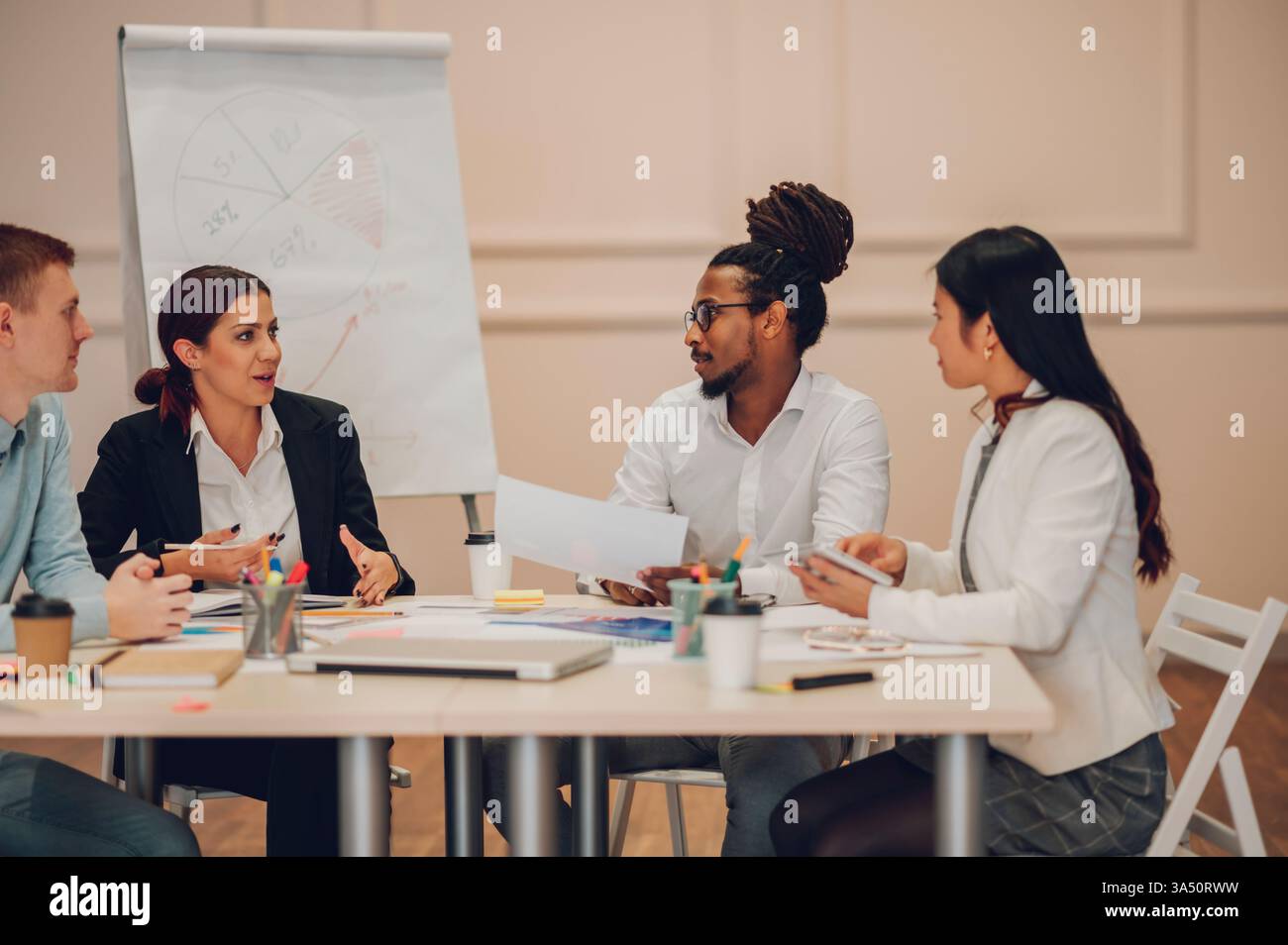 Young group of multiracial colleagues talking about company projects during a meeting in a ...