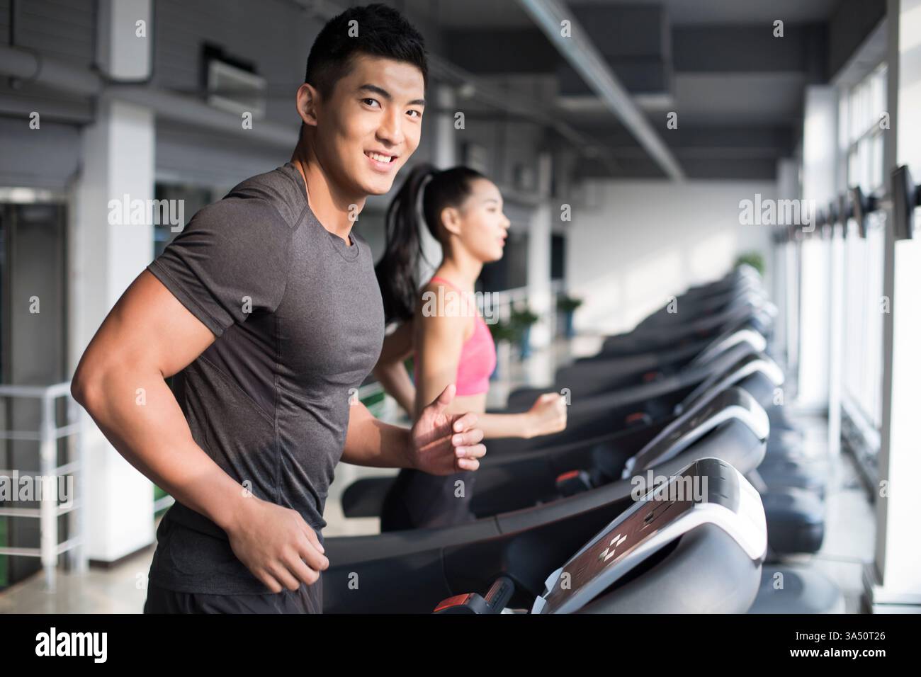 Smiling Chinese man with his wife exercising together running on ...
