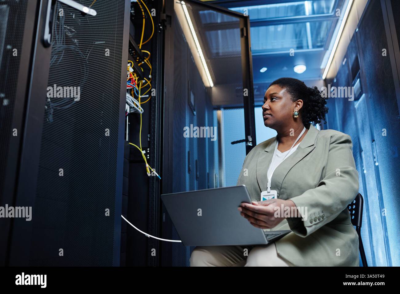 Low angle view at female IT engineer using laptop while setting up ...