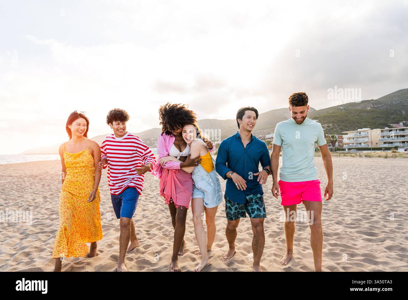 Cheerful diverse group of friends having fun walking together on sandy ...
