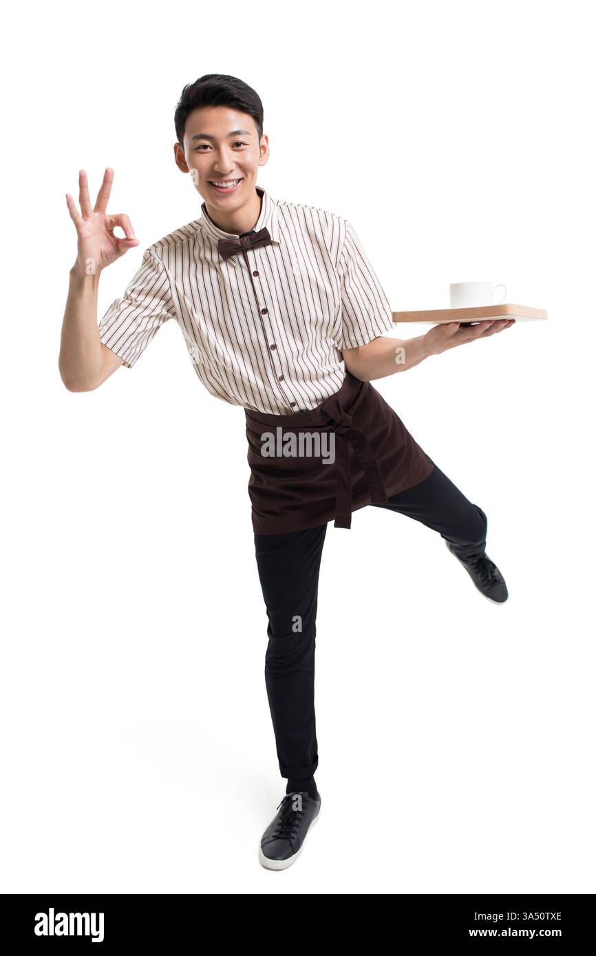 Smiling Chinese male waiter holding cup of coffee showing OK hand ...
