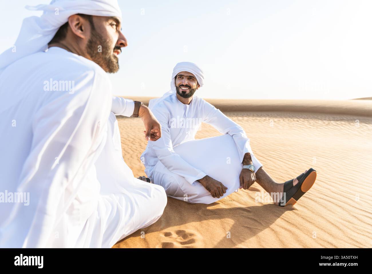 Two middle-eastern men wearing traditional emirati arab kandura bonding ...