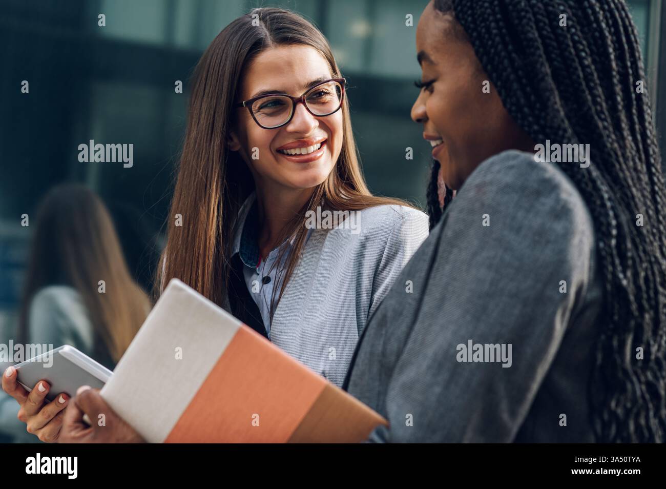 Smiling Black businesswoman with braids holding book talking to ...