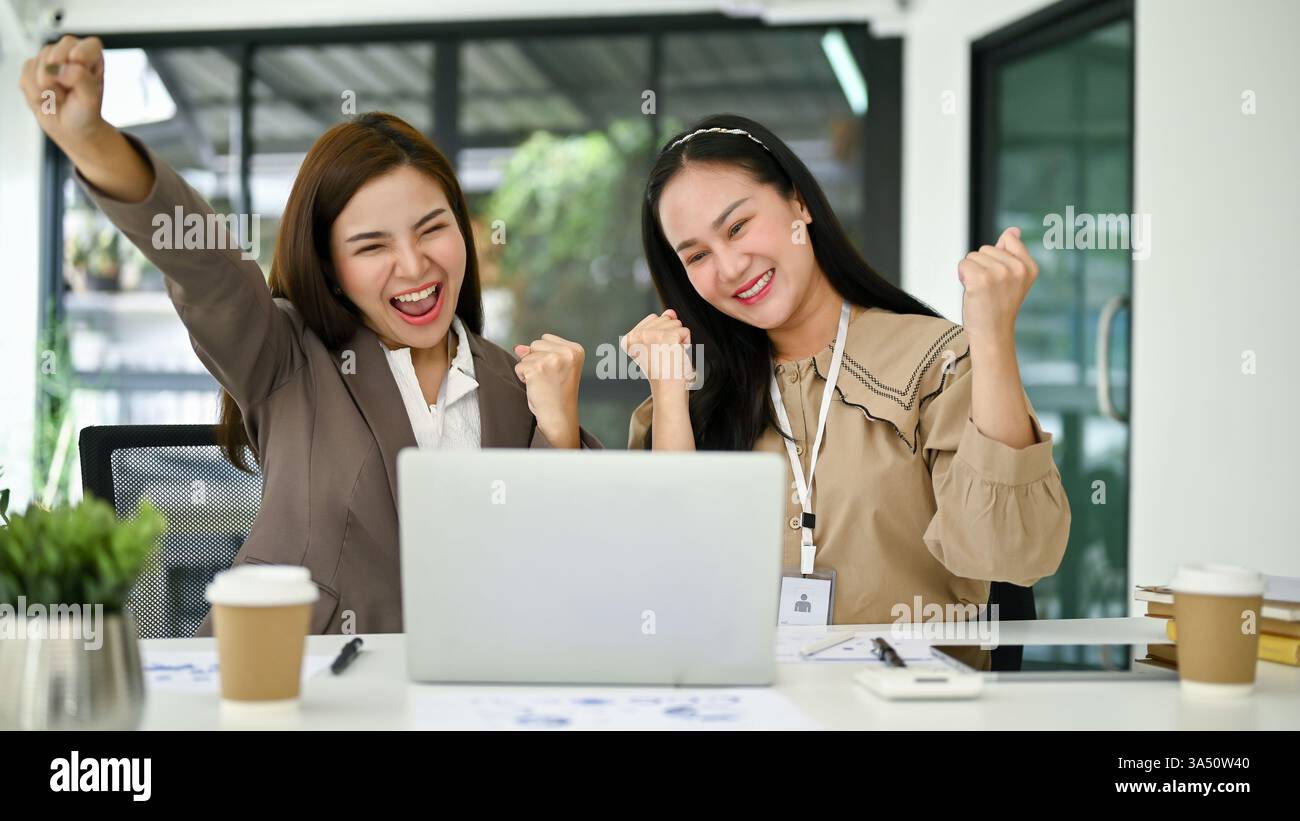 Two excited and overjoyed young Asian businesswomen screaming with joy ...