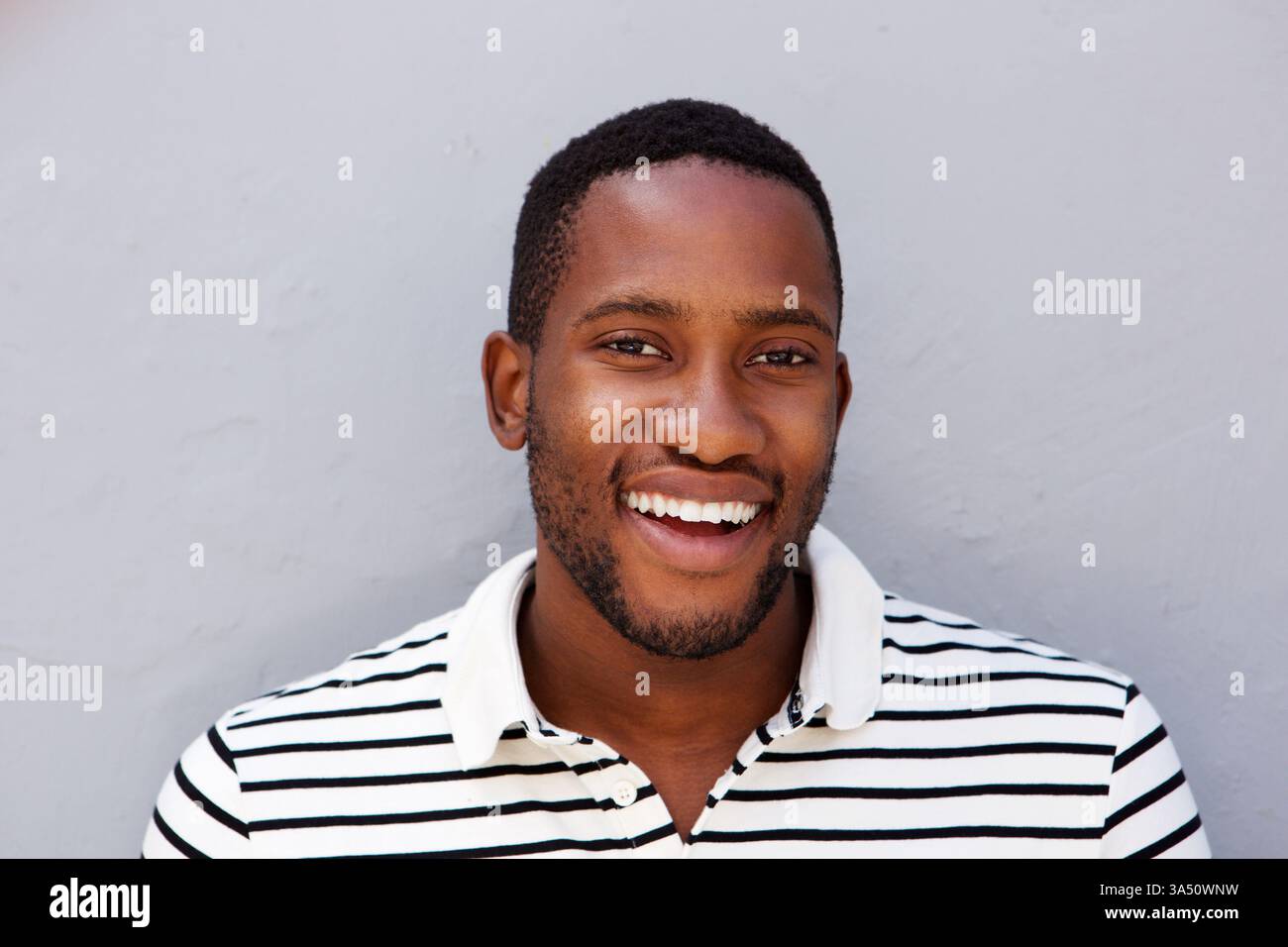 Close up portrait of cheerful african man smiling against gray wall ...