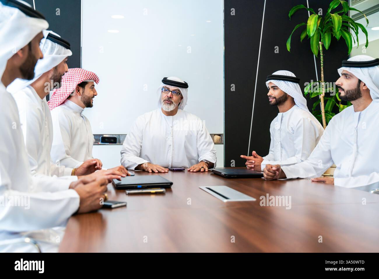 Group of Arab businessmen in Kanduras gather in a Dubai meeting room ...