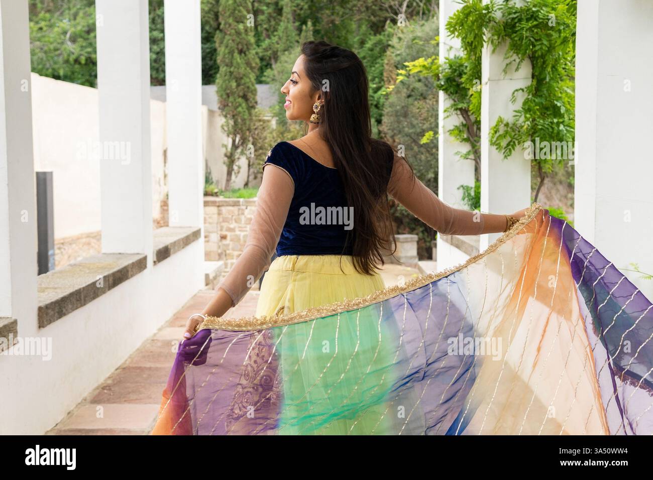 Back view of smiling young woman with long hair in traditional sari ...