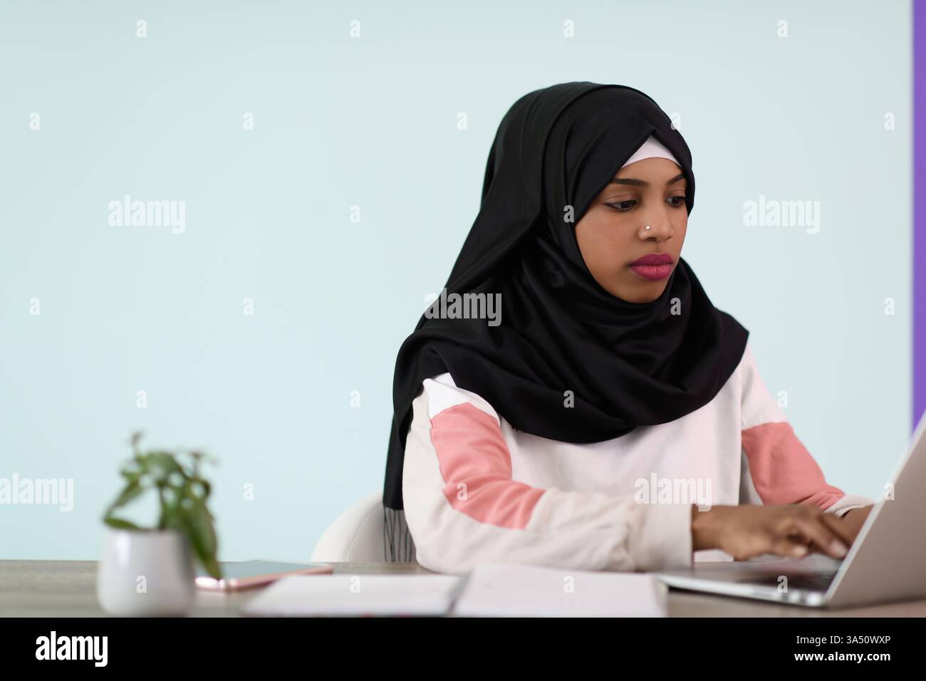 Serious Black Muslim business woman with nose piercing wearing hijab ...