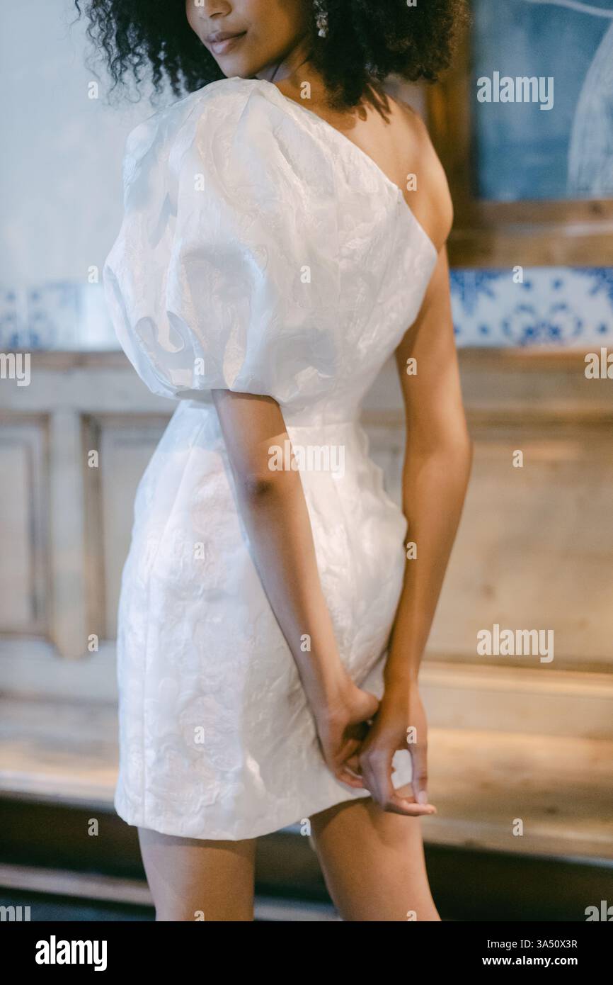 Model poses in elegant one-shoulder white dress while showcasing unique ...