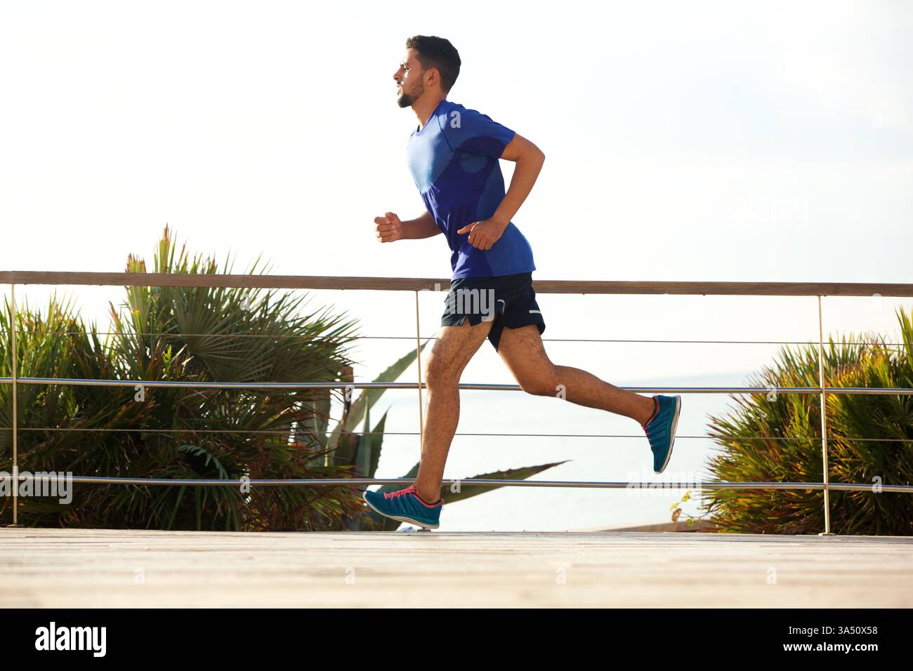 Full length profile portrait of young man running outside Stock Photo ...