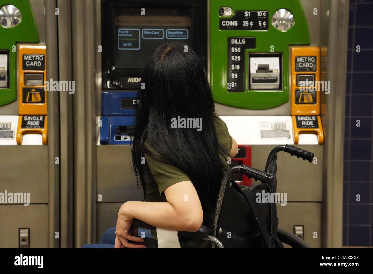 Disabled Asian woman in wheelchair using ATM machine in train station ...
