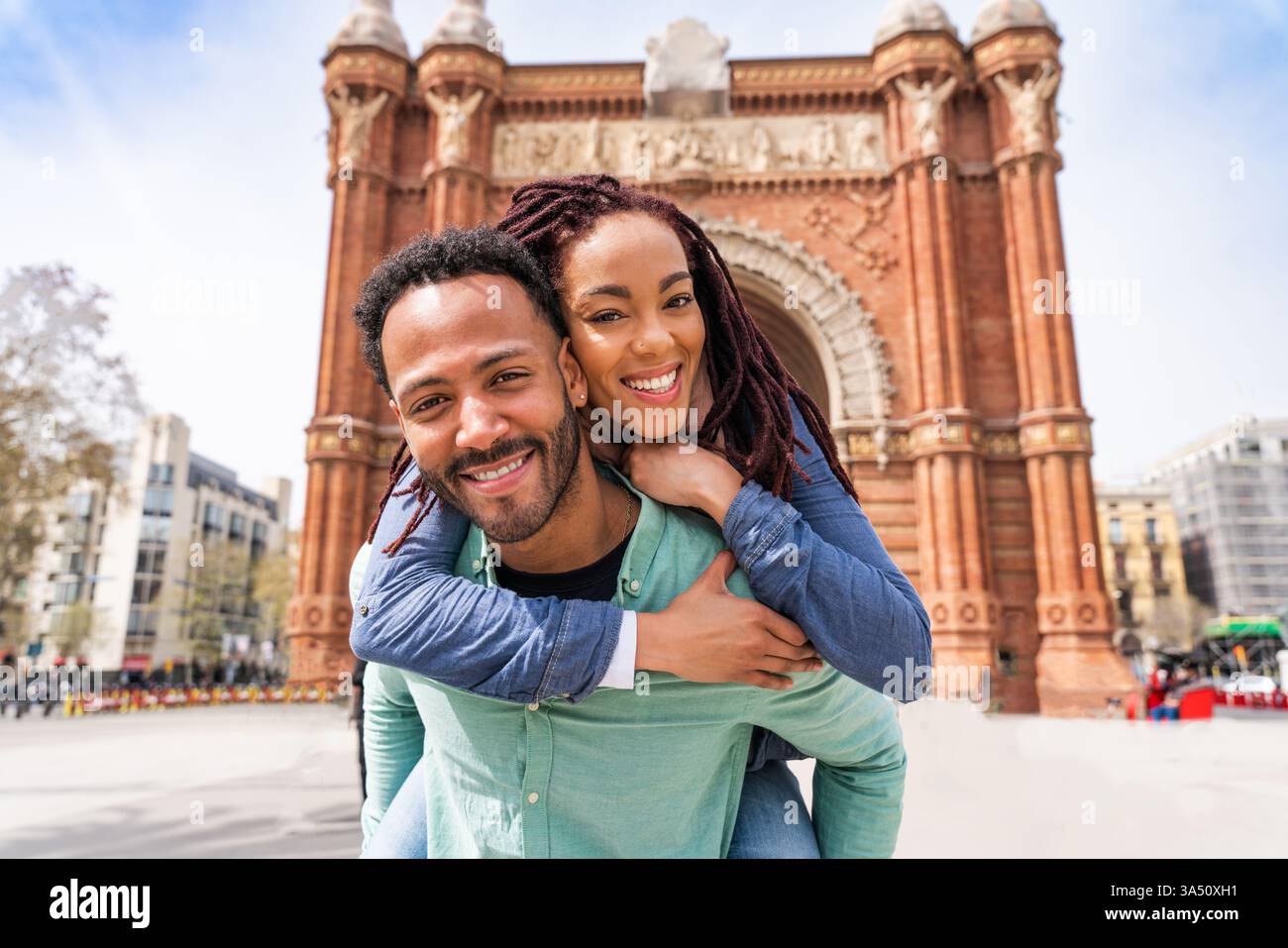 Smiling Hispanic couple in Barcelona share a playful piggyback moment ...