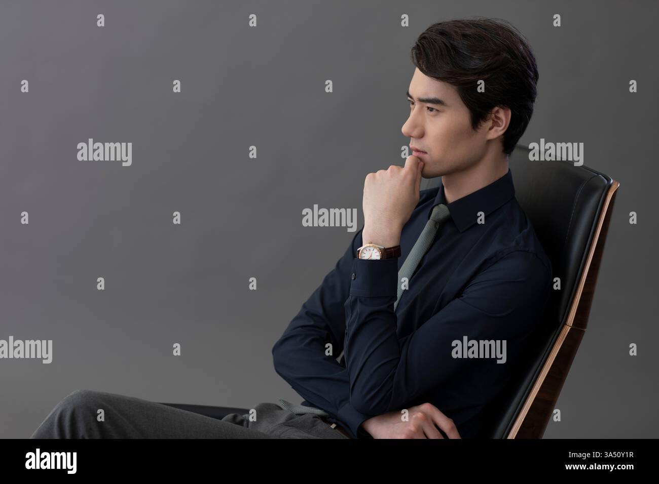 Serious Chinese businessman with hand on chin looking away thinking ...