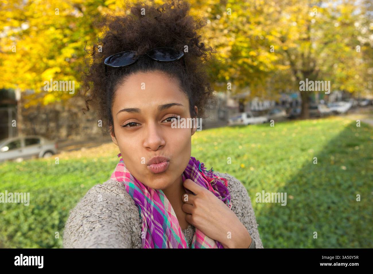 African American woman pouting lips taking selfie standing in park ...
