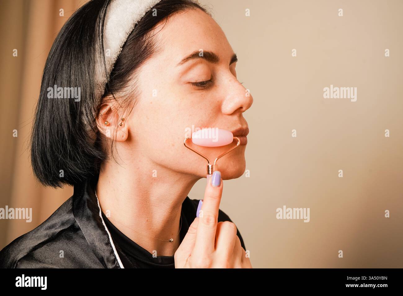 Using a facial roller, a woman massages her jawline. A soothing ...