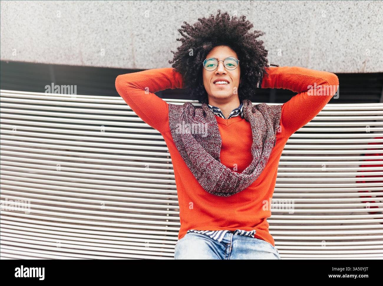 A handsome young Egyptian curly guy sitting on a bench dressed in a ...