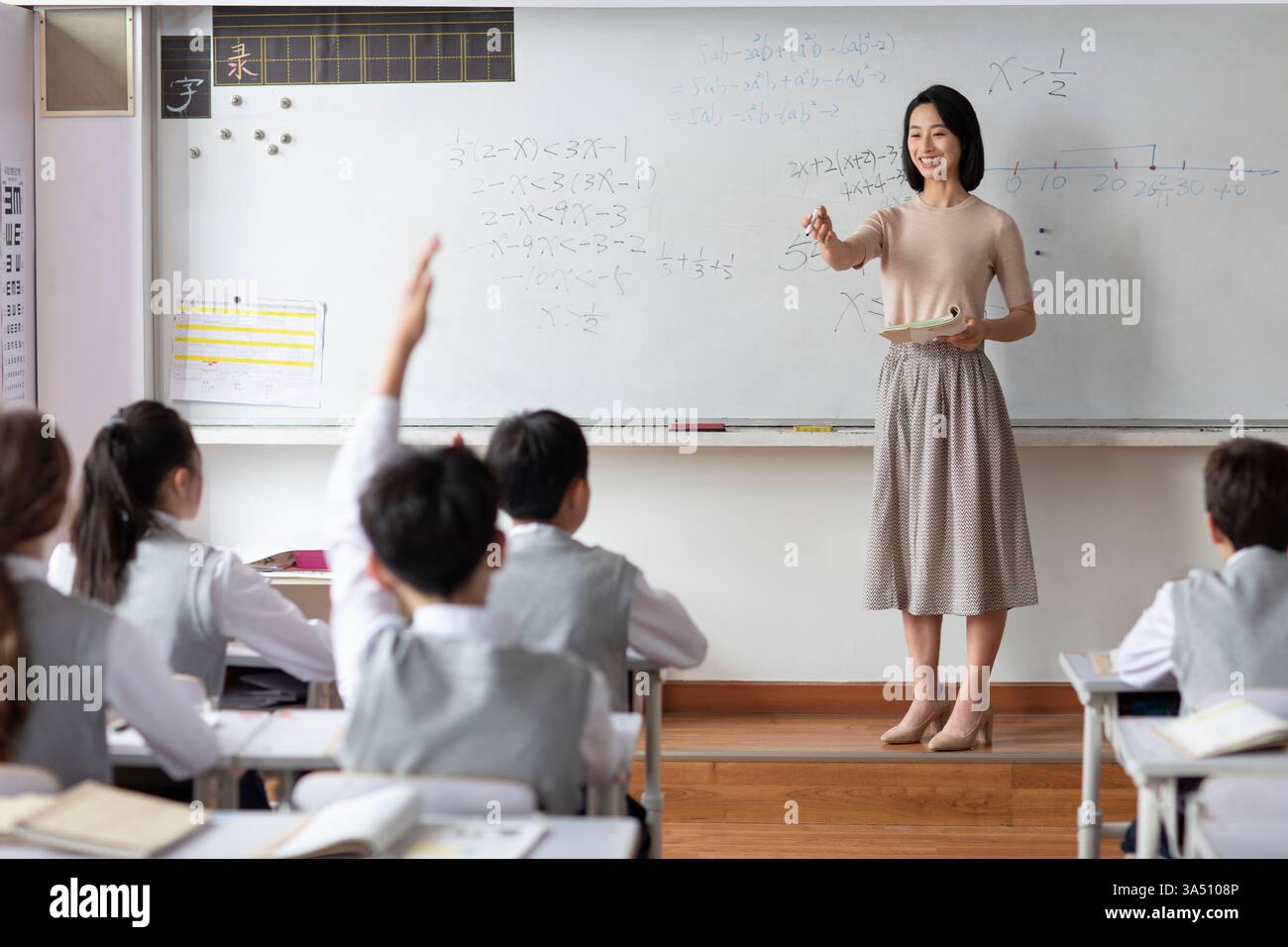 Chinese female teacher teaching students standing in front of ...