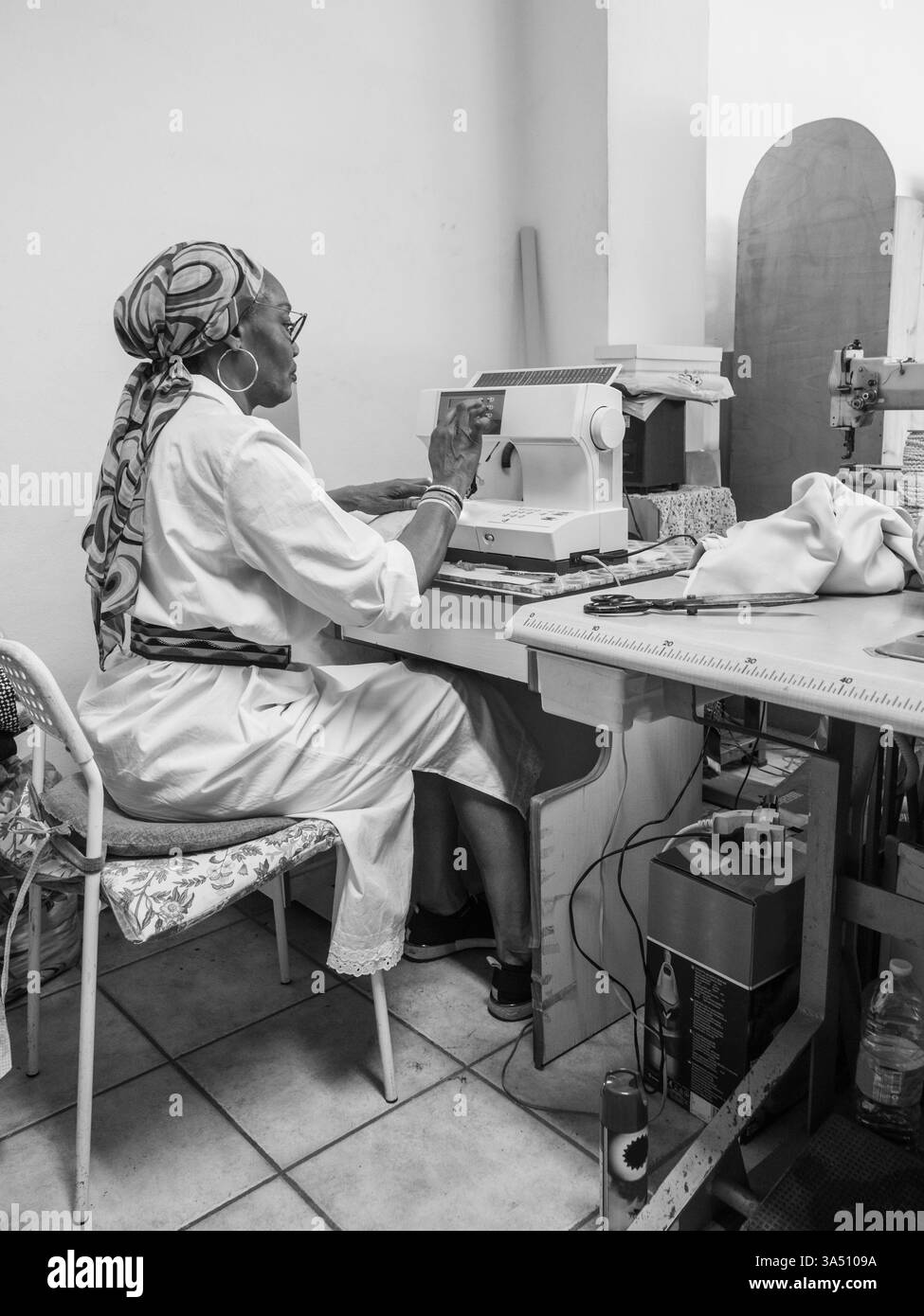 African seamstress at a sewing machine, stitching a shirt with ...