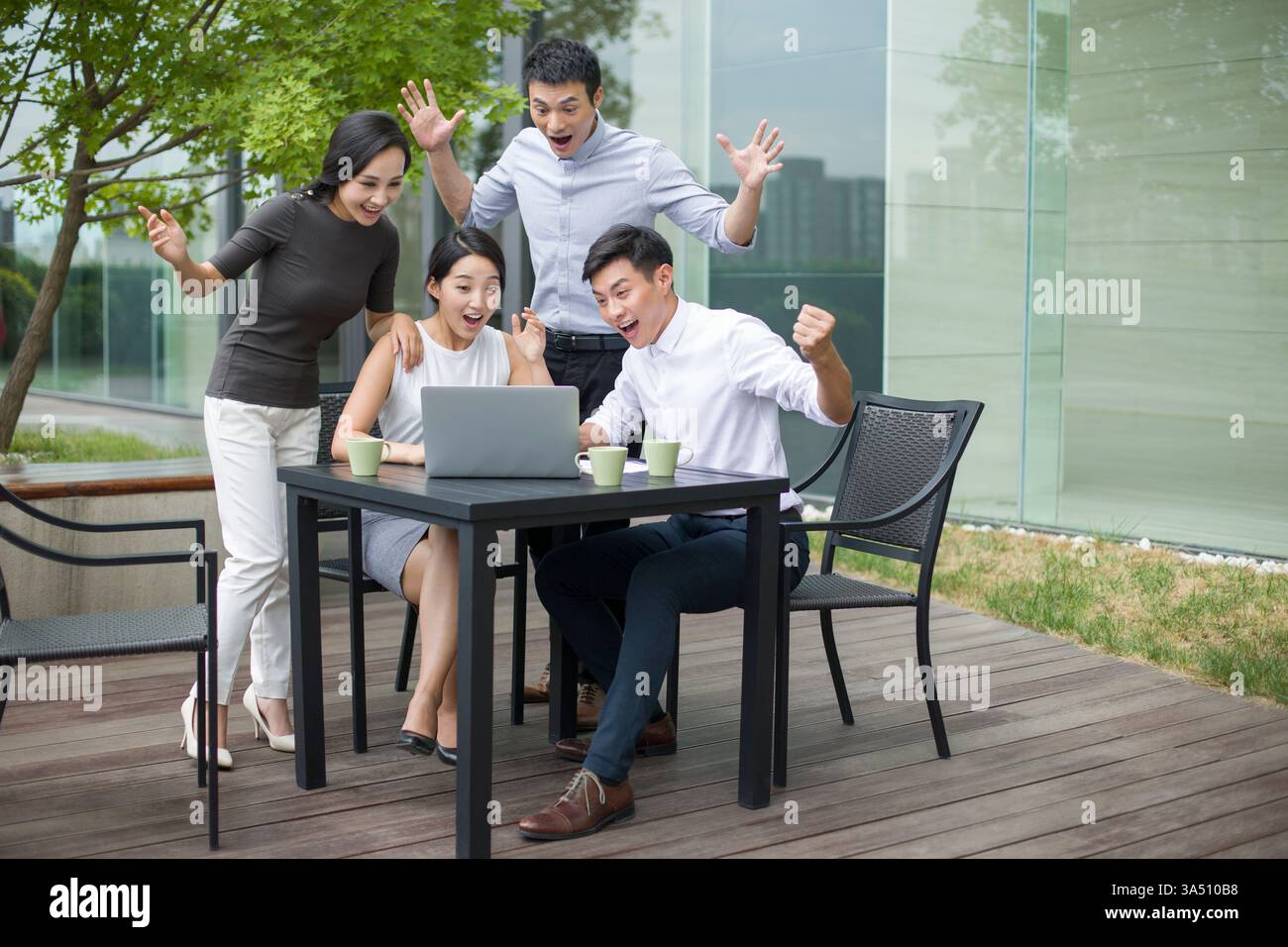Chinese office workers with laptop raising closed fists celebrating ...