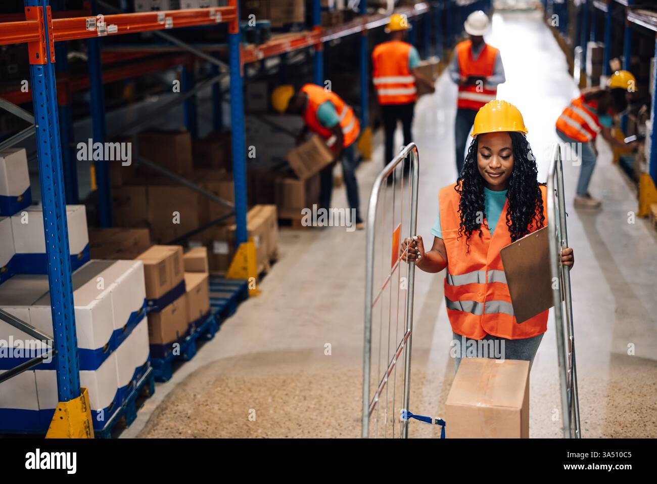 Warehouse worker is pushing a cart full of boxes and checking her ...