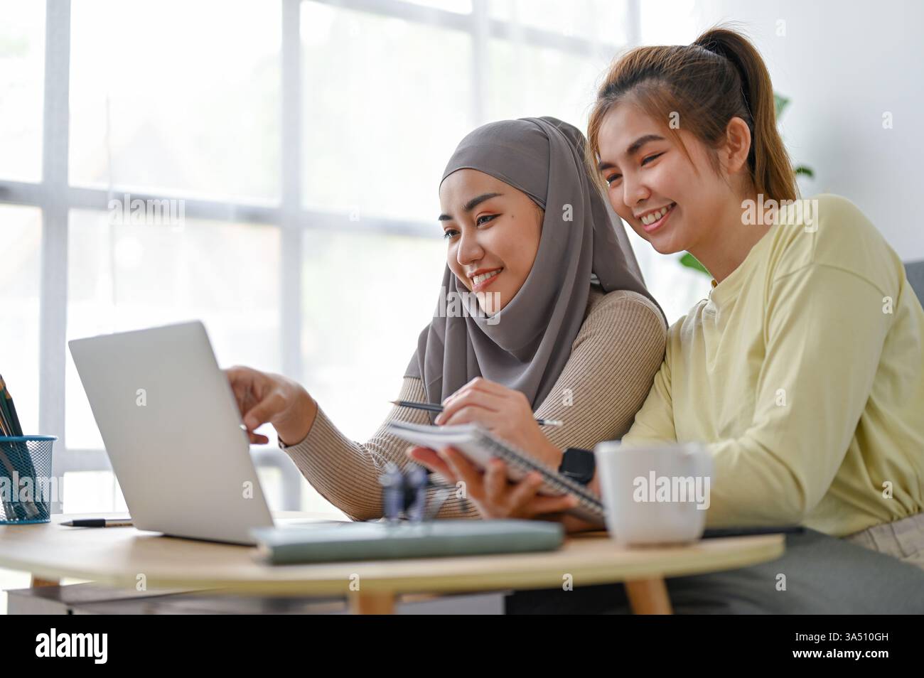 Cheerful Muslim woman and her friend watching movies together in their ...