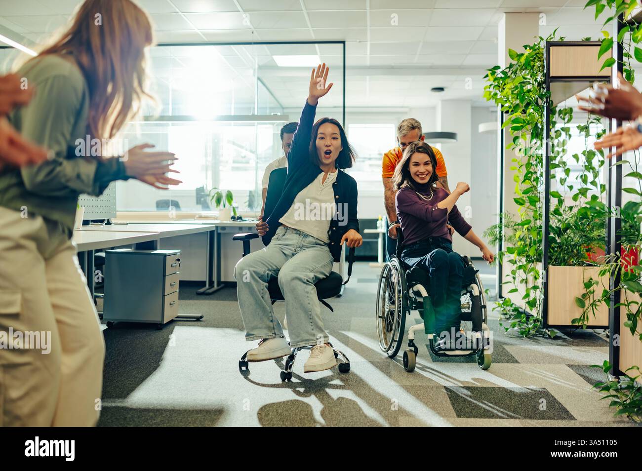 Multiracial business team having fun while racing on office chairs ...