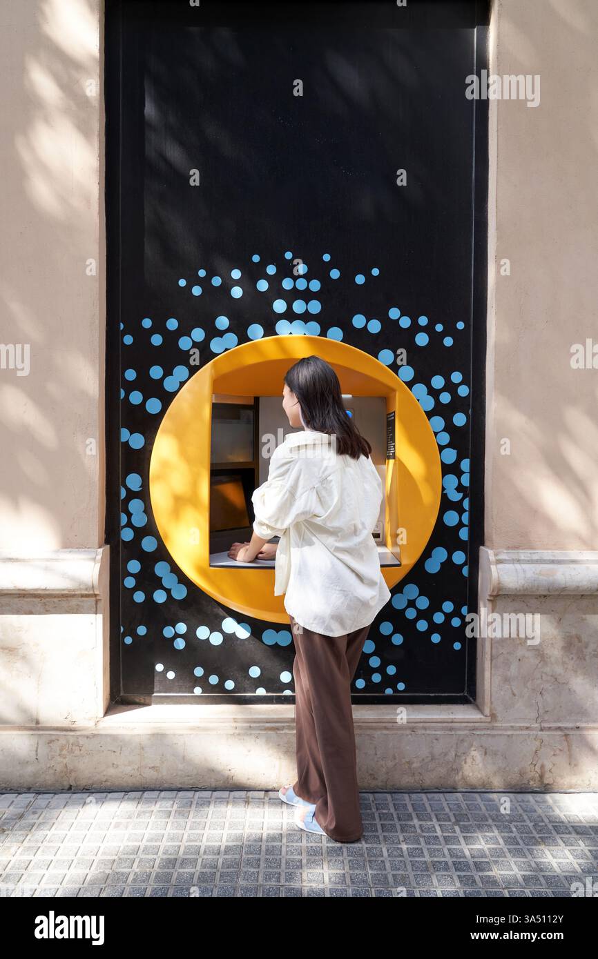 Japanese woman standing on street and withdrawing money from ATM ...