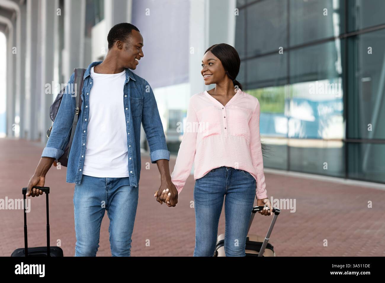Happy African couple walking hand in hand near an airport with ample ...