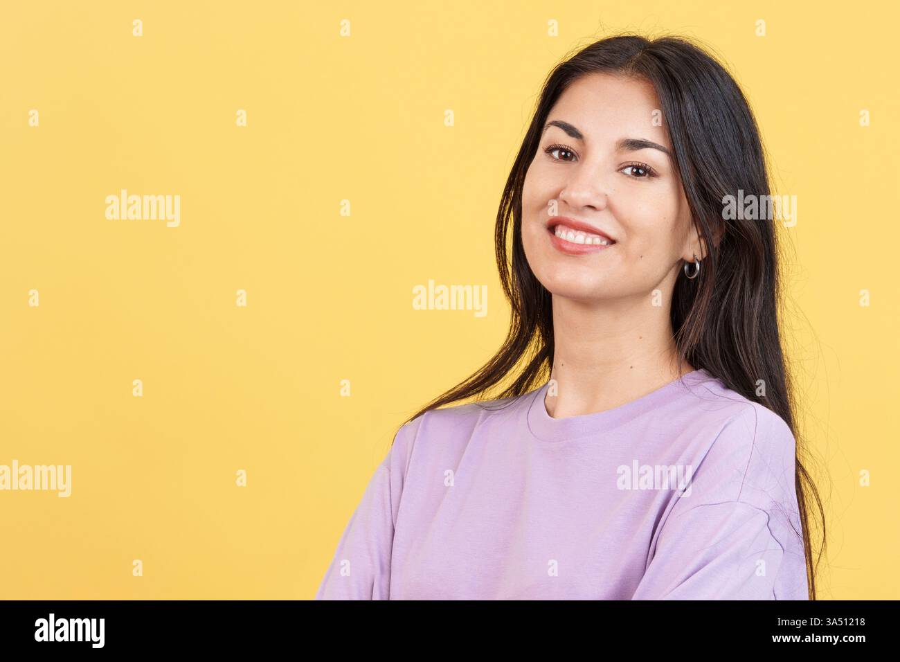Happy hispanic woman smiling at the camera in studio with yellow ...