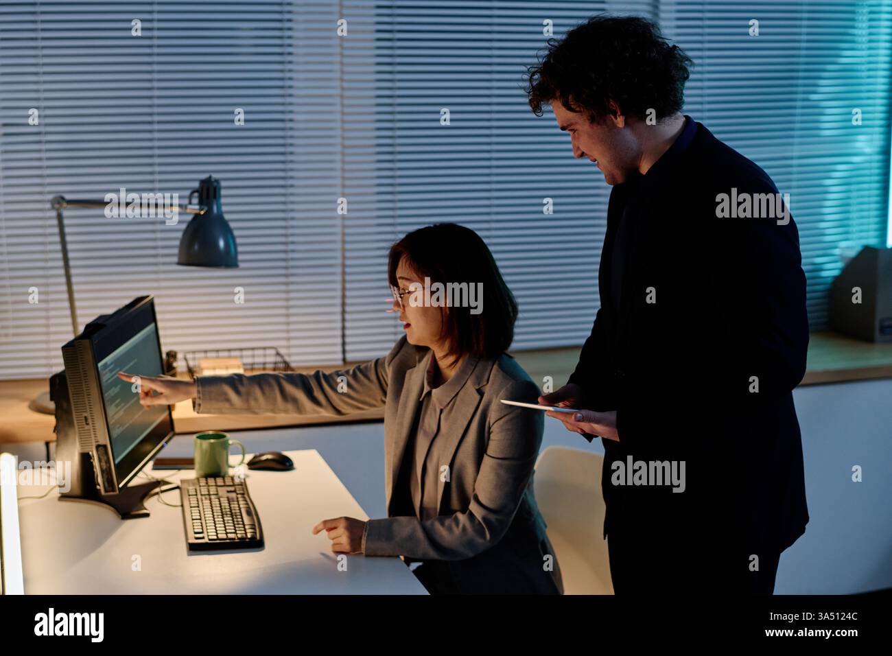 Young woman pointing at computer monitor with codes and discussing ...