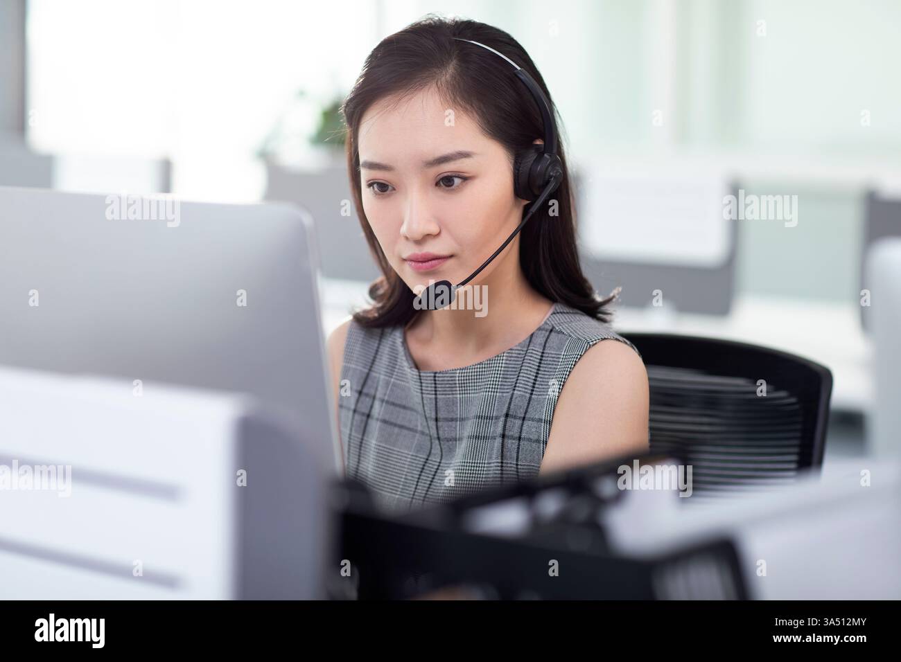 Smiling Chinese female customer support wearing headset answering ...