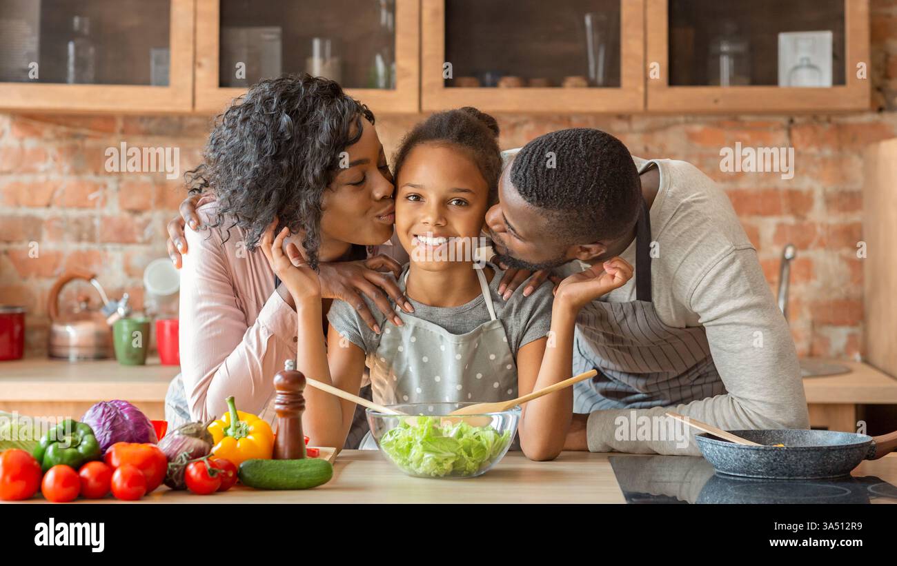 Adorable black family cooking healthy dinner together at kitchen ...