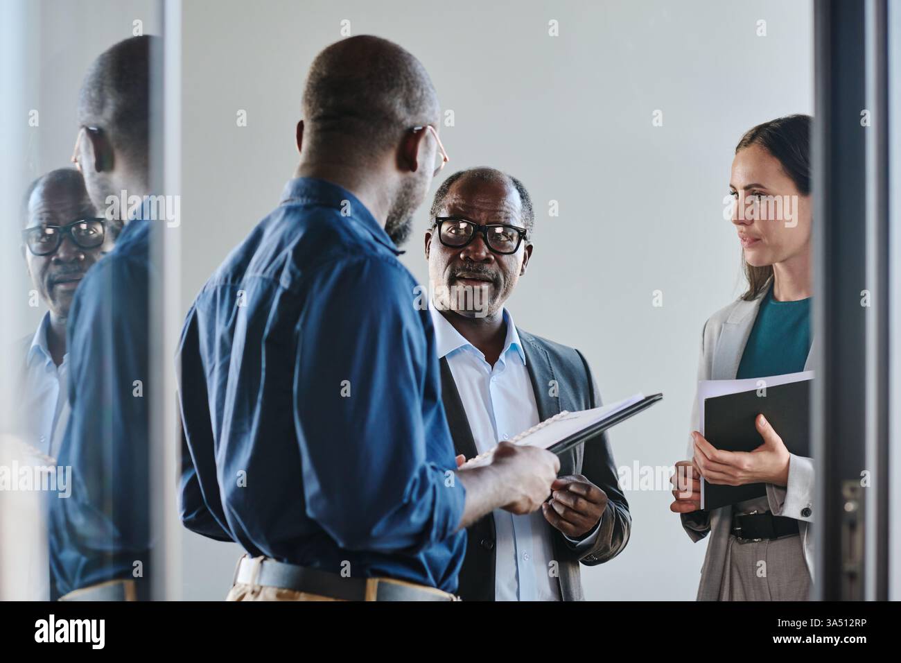 Middle-aged Black male boss having meeting with male and female ...