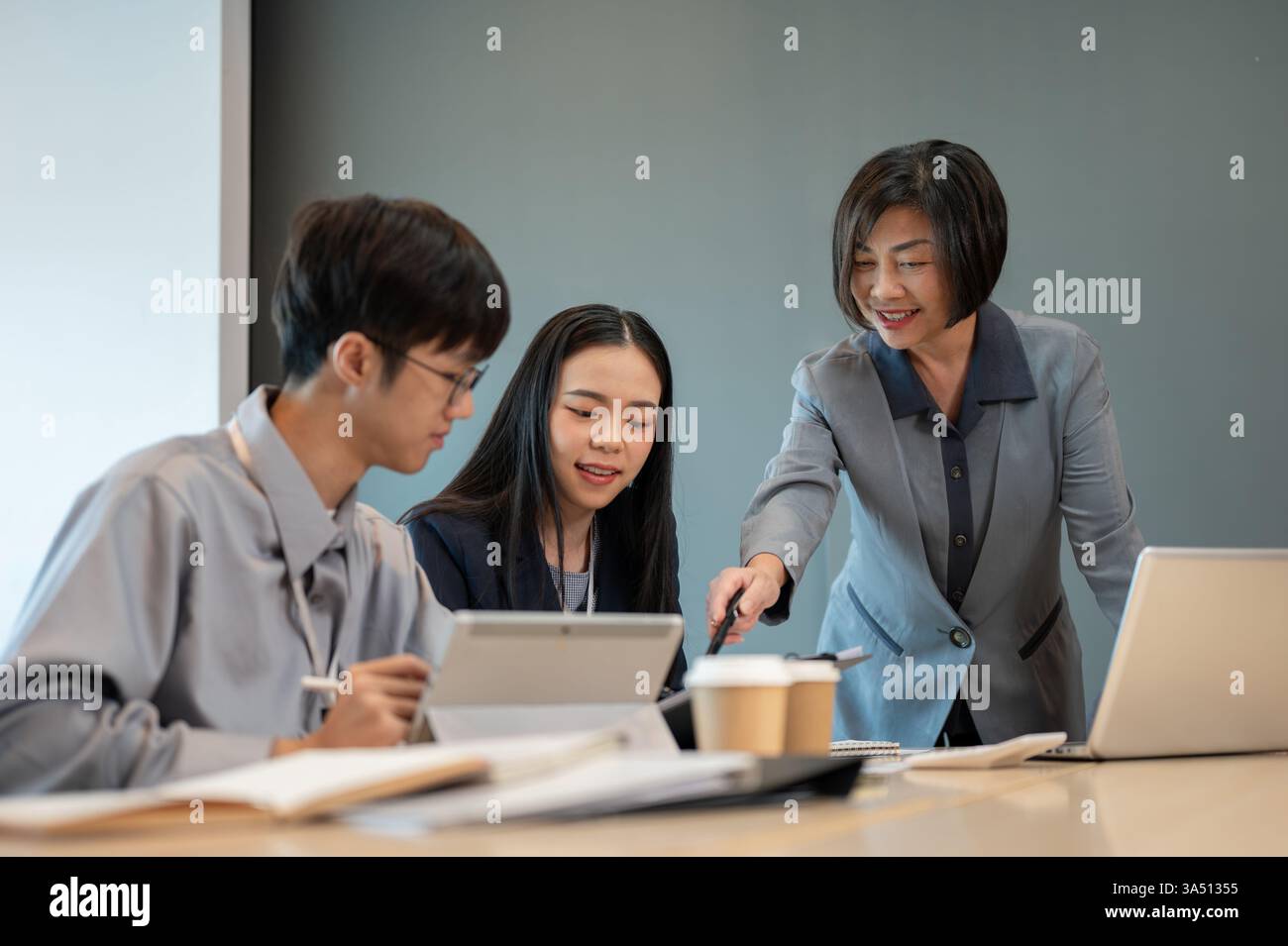 Smiling middle-aged Asian female boss standing and discussing new ...