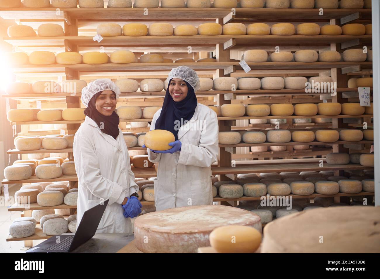 Smiling Middle Eastern female workers in hijab and white uniforms ...