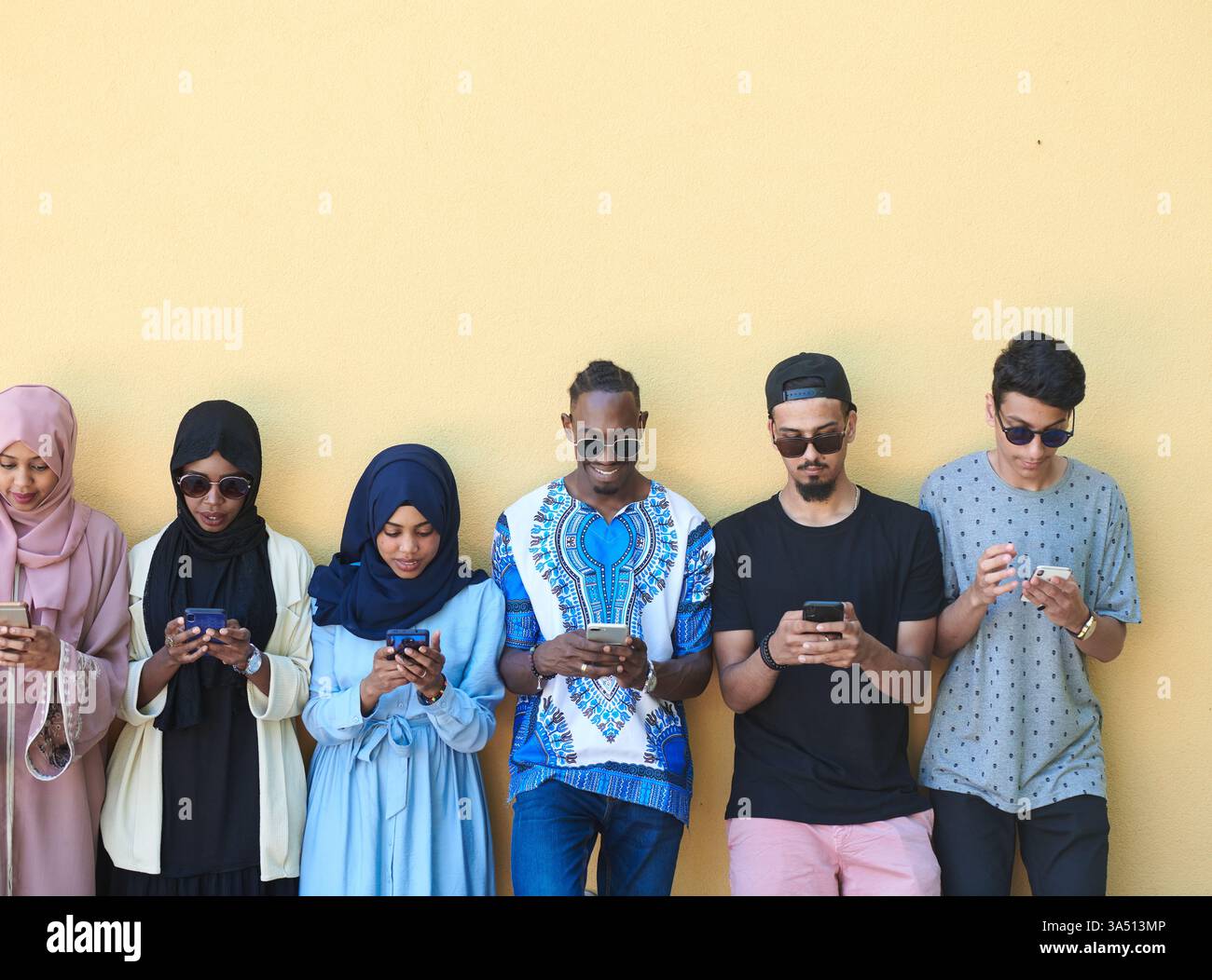 Diverse group of friends using their smartphones while standing ...