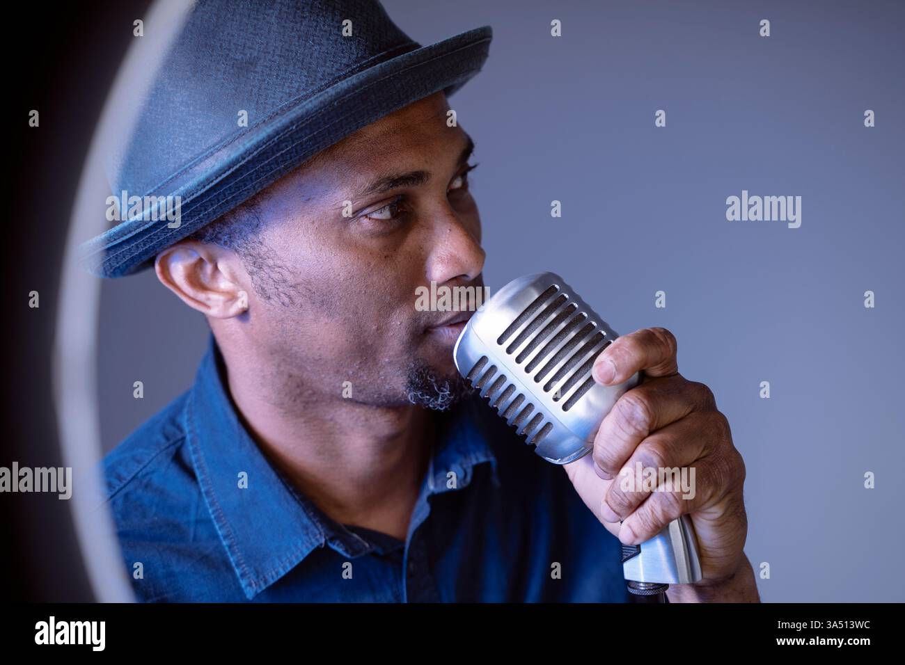 Black male music performer in ring light frame looking away singing ...