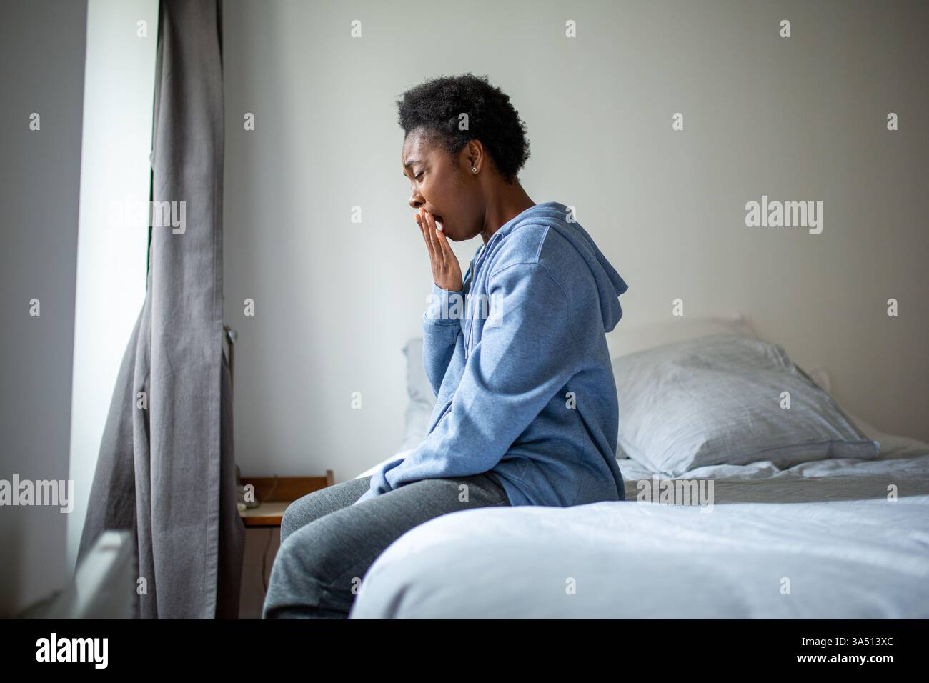 Afro haired Black woman waking up in bed during day time Stock Photo ...