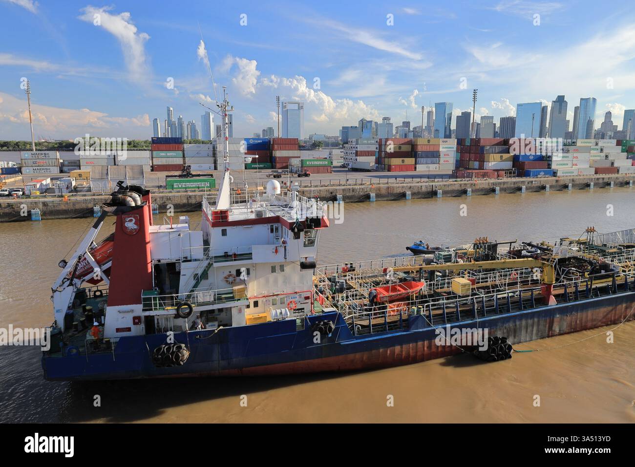 Commercial ship cruising past a wharf with containers stacked up at the ...